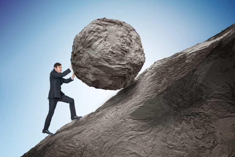Sisyphus metaphore. Young businessman pushing heavy stone boulder up on ...